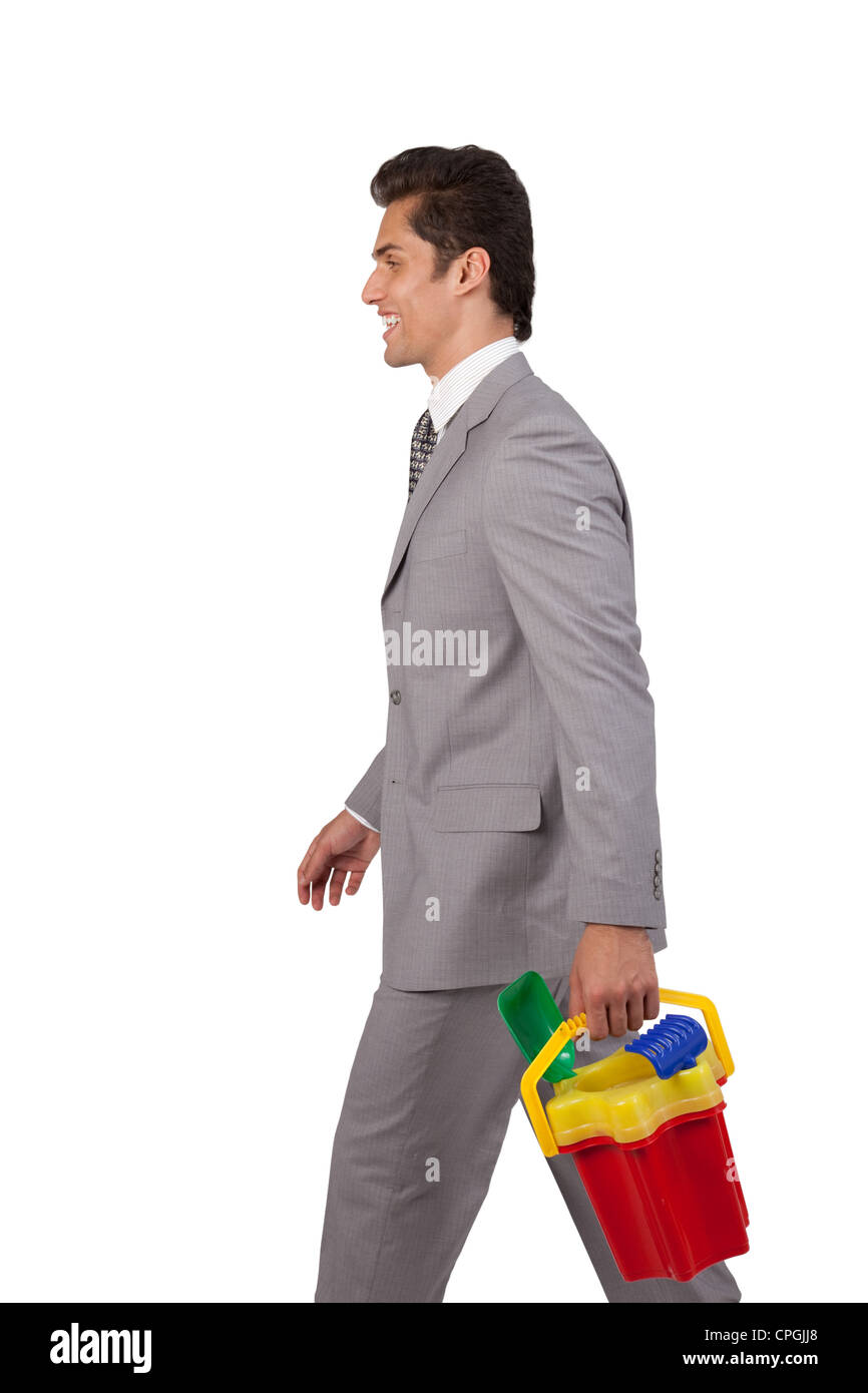 Businessman with small bucket walking Stock Photo - Alamy