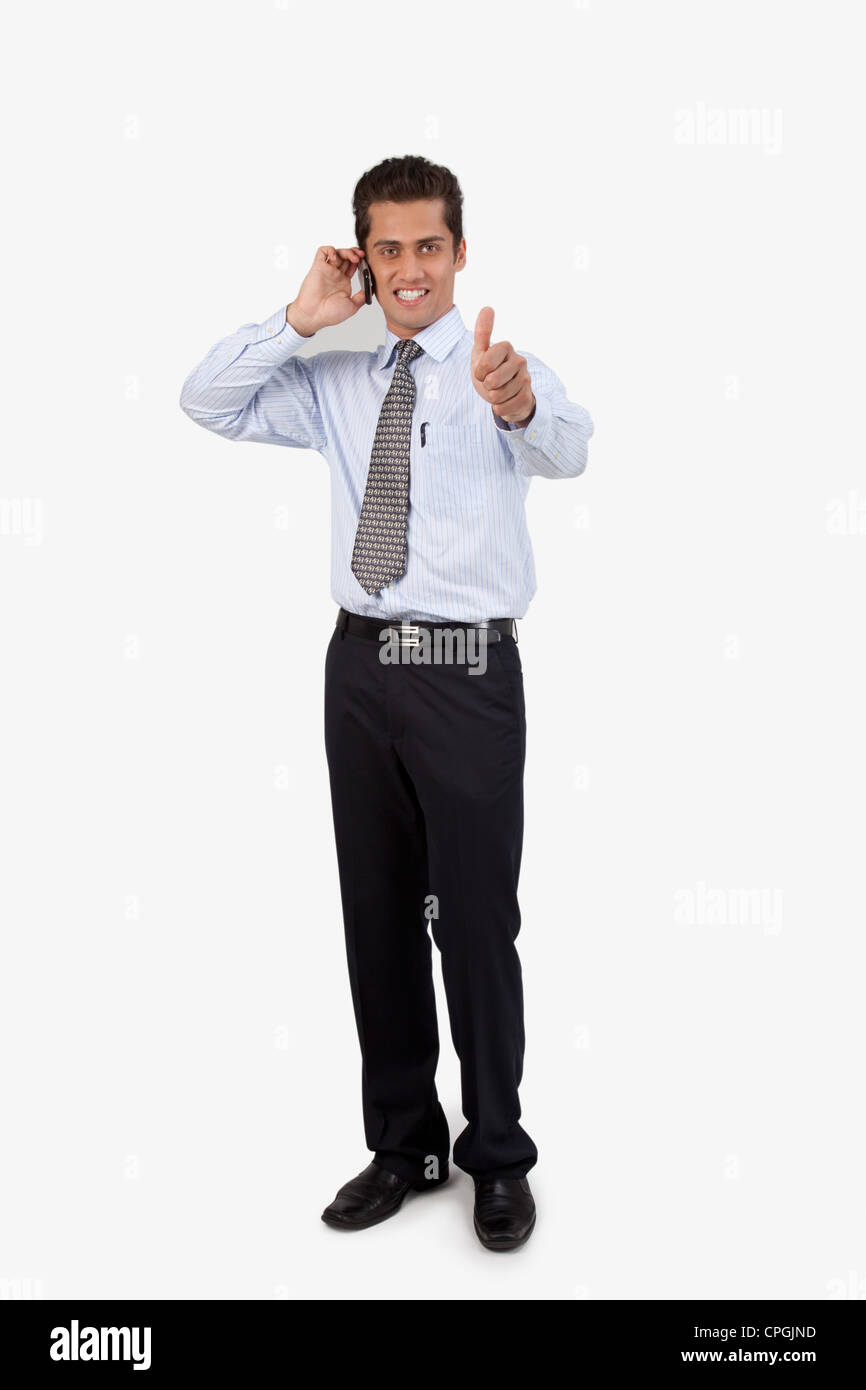 Businessman using mobile phone, giving a thumbs up Stock Photo - Alamy
