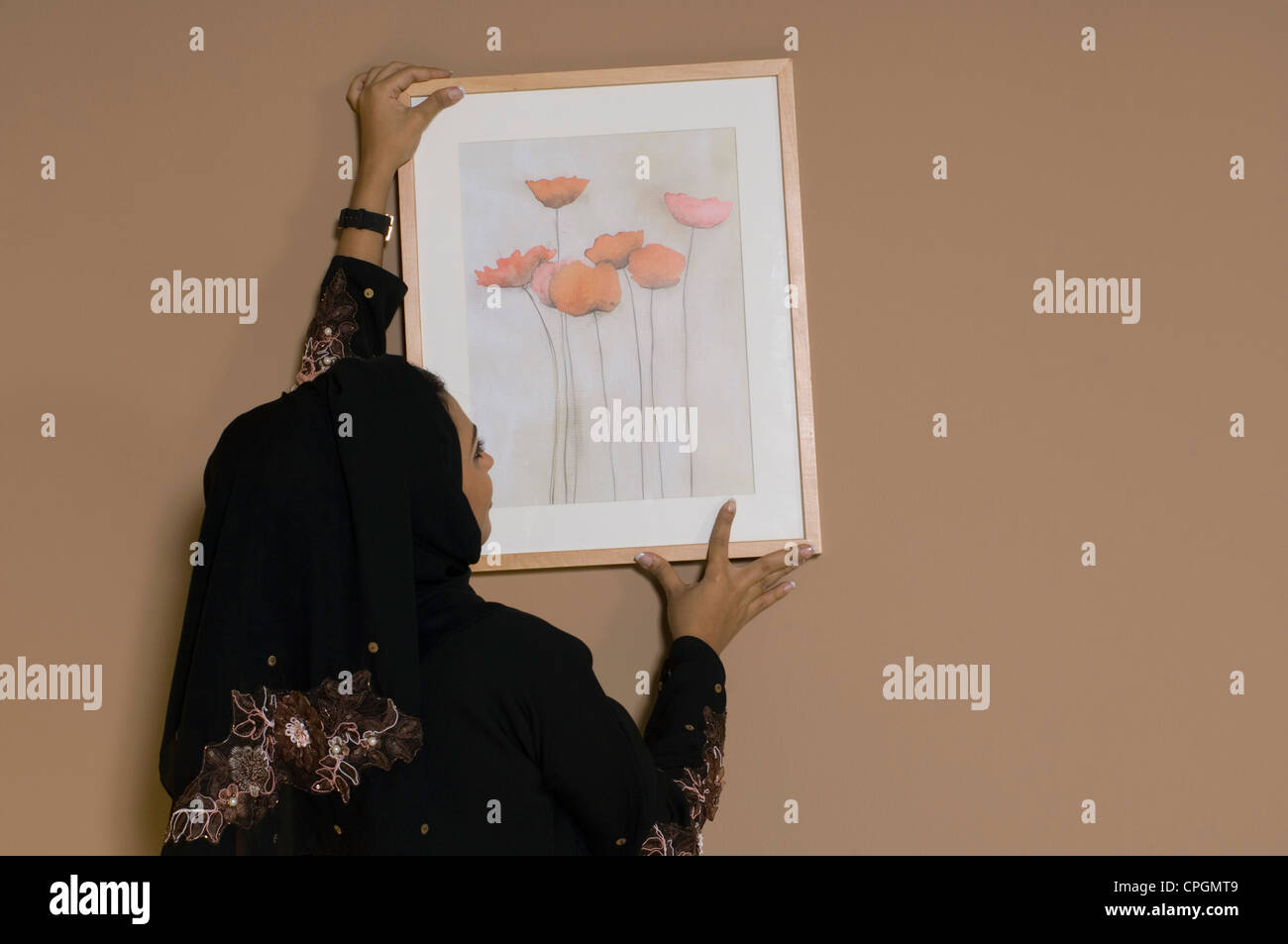 Young woman adjusting picture frame Stock Photo - Alamy