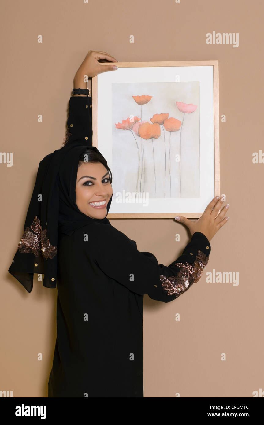 Young woman adjusting picture frame, portrait Stock Photo - Alamy