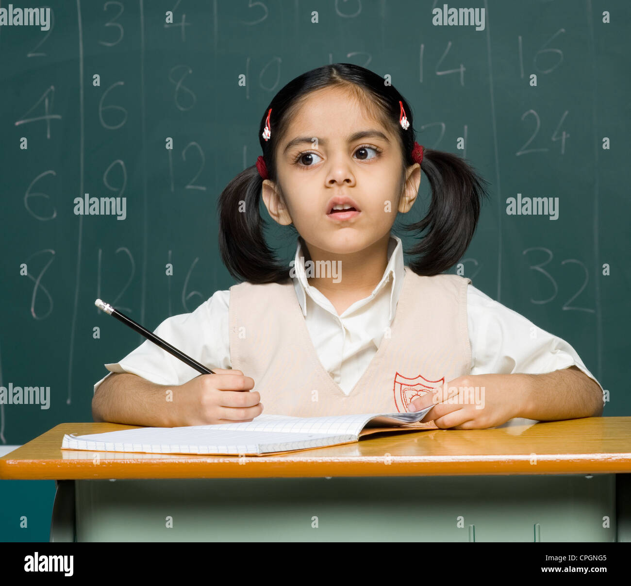 Girl (6-7) holding pencil, contemplating Stock Photo - Alamy