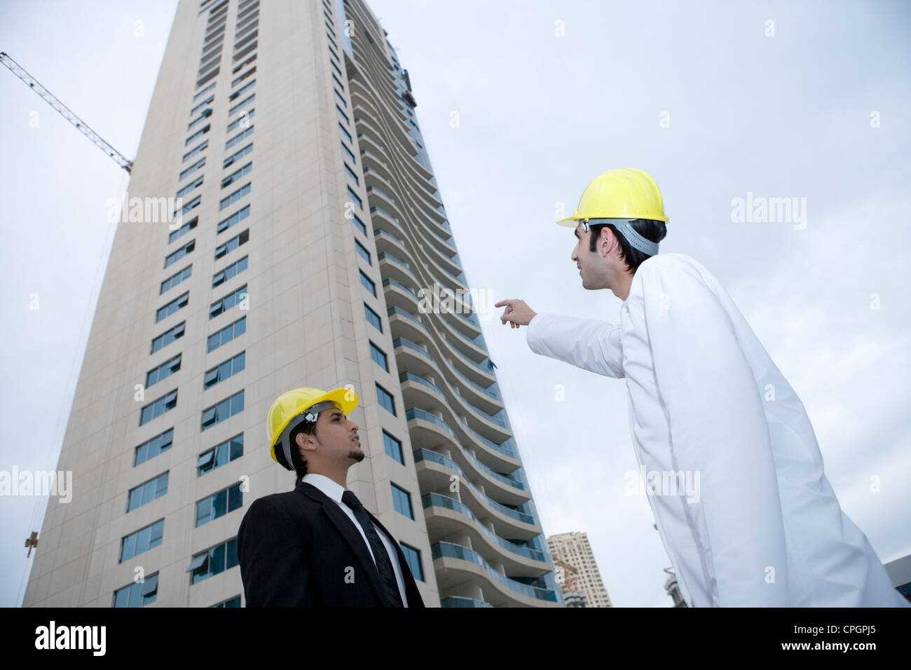 Businessmen pointing at building, low angle view Stock Photo - Alamy