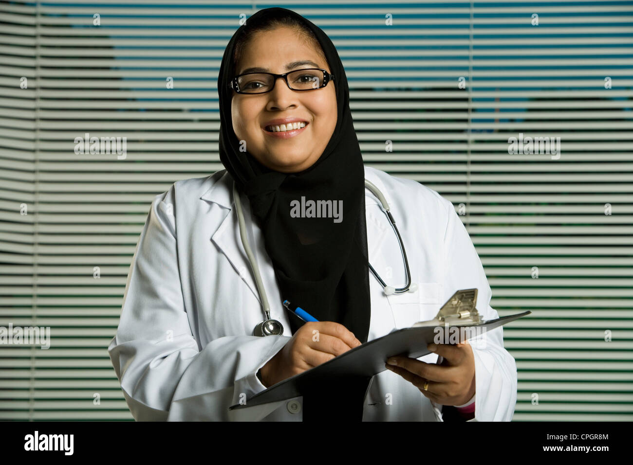 Female doctor writing on pad, smiling, portrait Stock Photo - Alamy