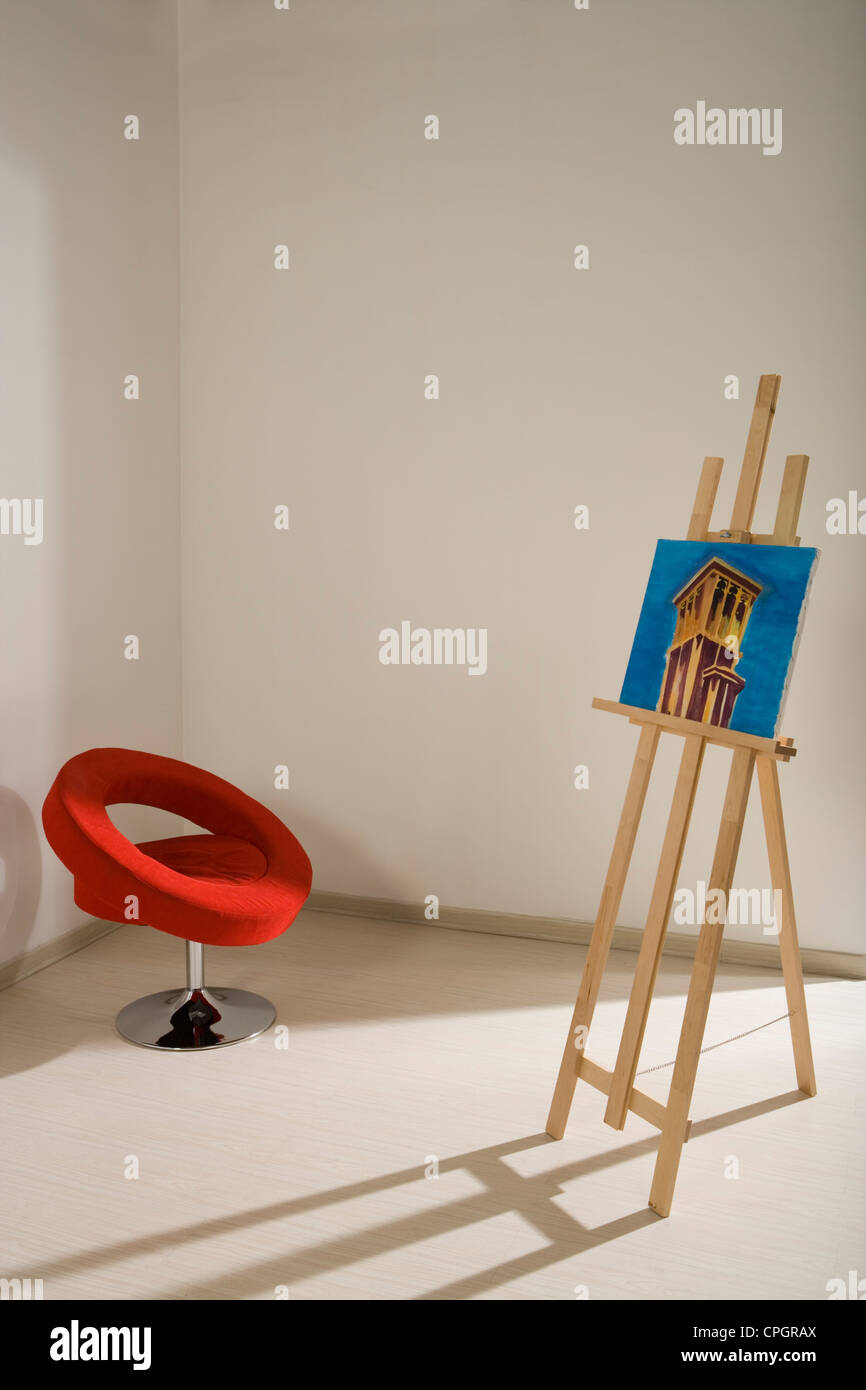 Easel with painting by swivel chair Stock Photo - Alamy
