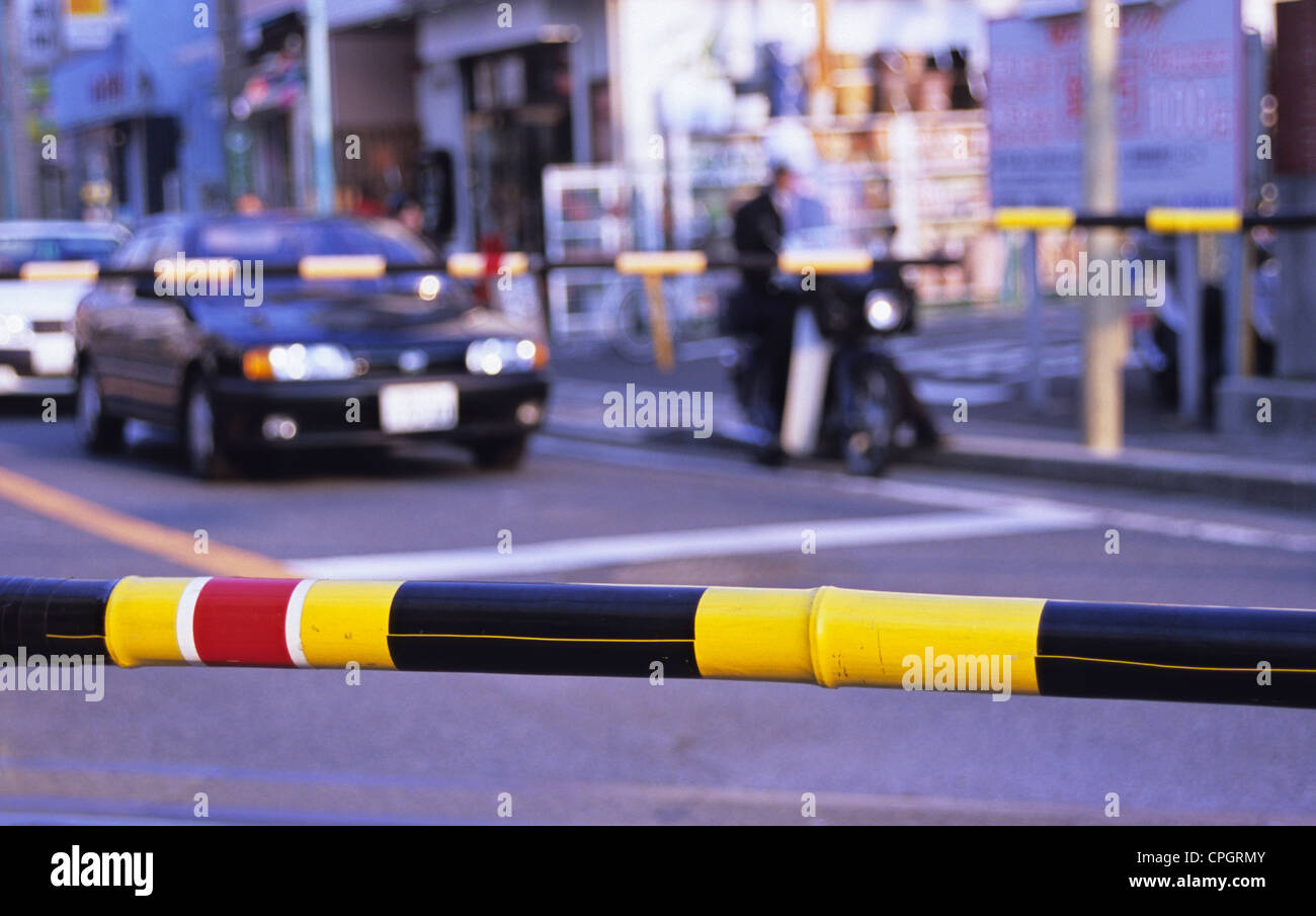 Vehicles waiting at a railway crossing with bamboo barriers, Kamakura ...