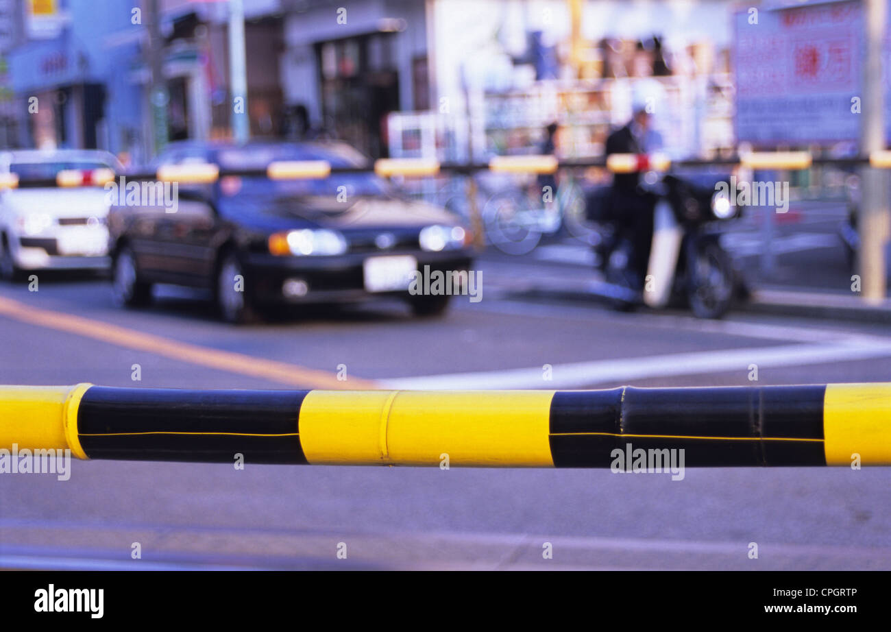 Vehicles waiting at a railway crossing with bamboo barriers, Kamakura ...