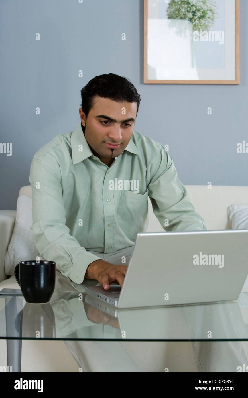 Man sitting on sofa and using laptop Stock Photo - Alamy