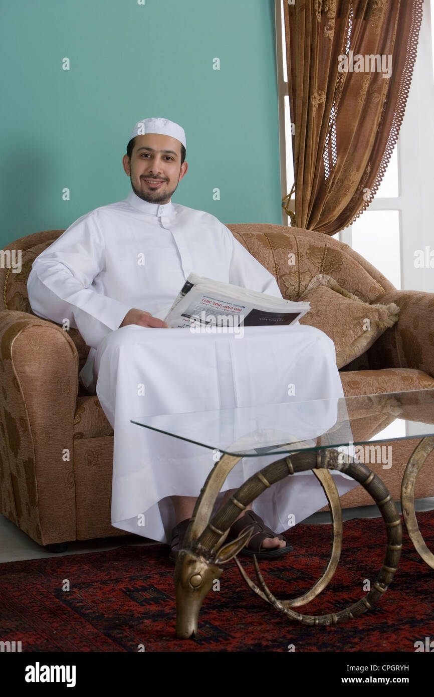 Arab man sitting in a sofa holding a newspaper Stock Photo - Alamy