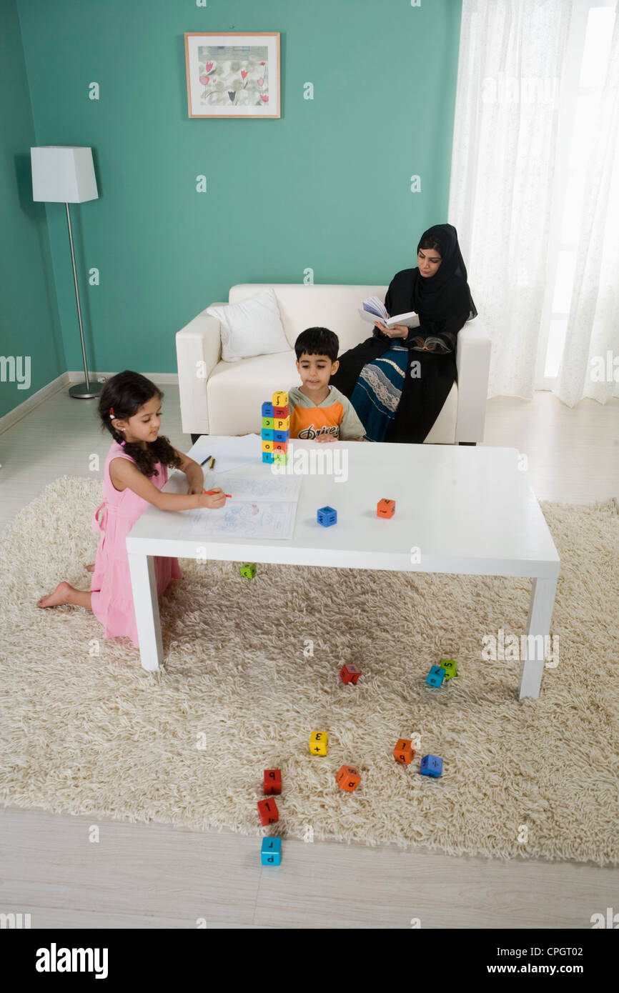 Arab Mother reading, children playing at home Stock Photo - Alamy