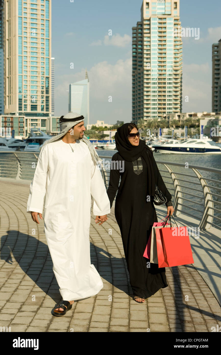 Arab couple holding hands while walking, woman with shopping bags, at ...