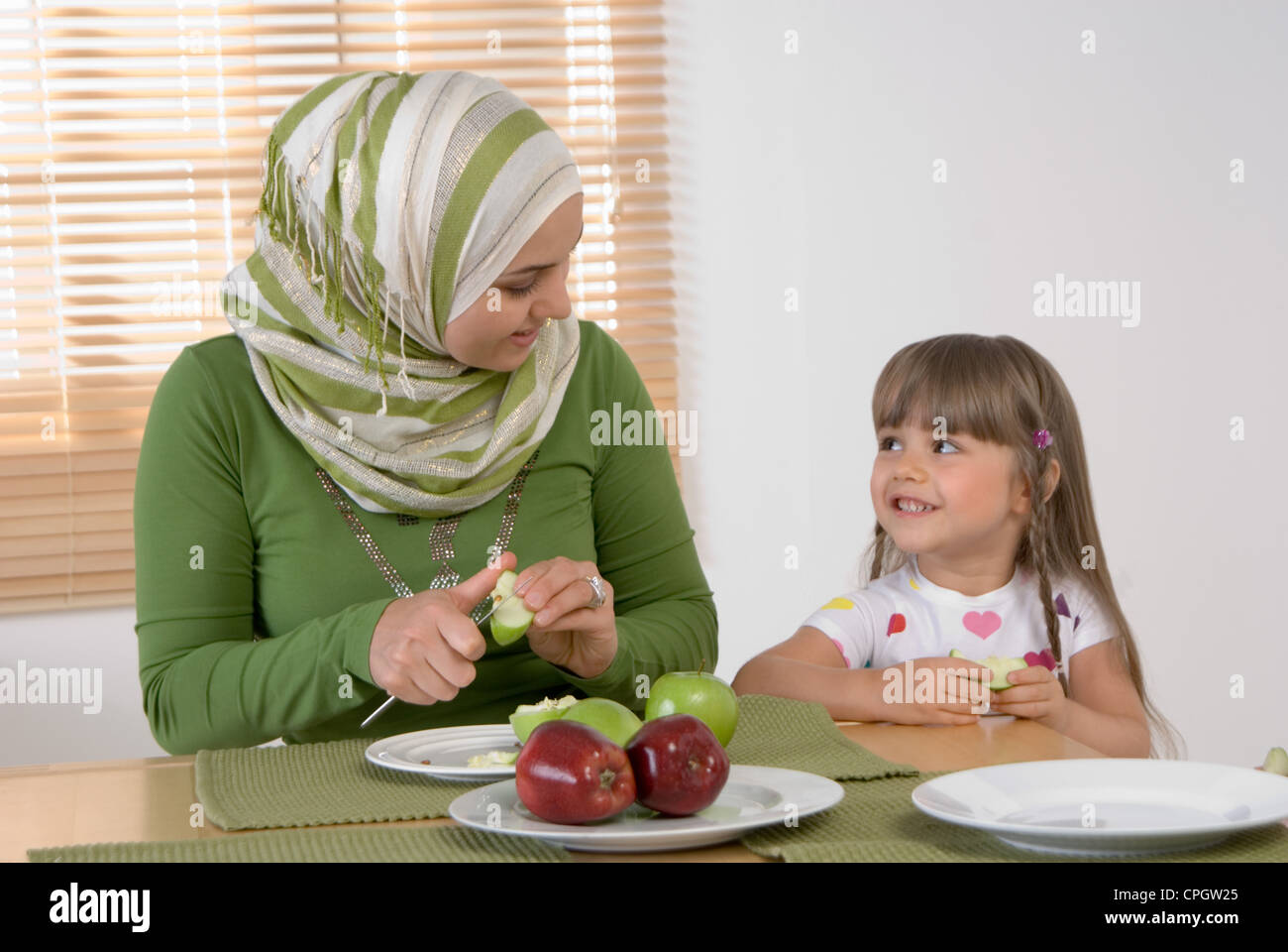 Arab woman and daughter eating apple Stock Photo - Alamy