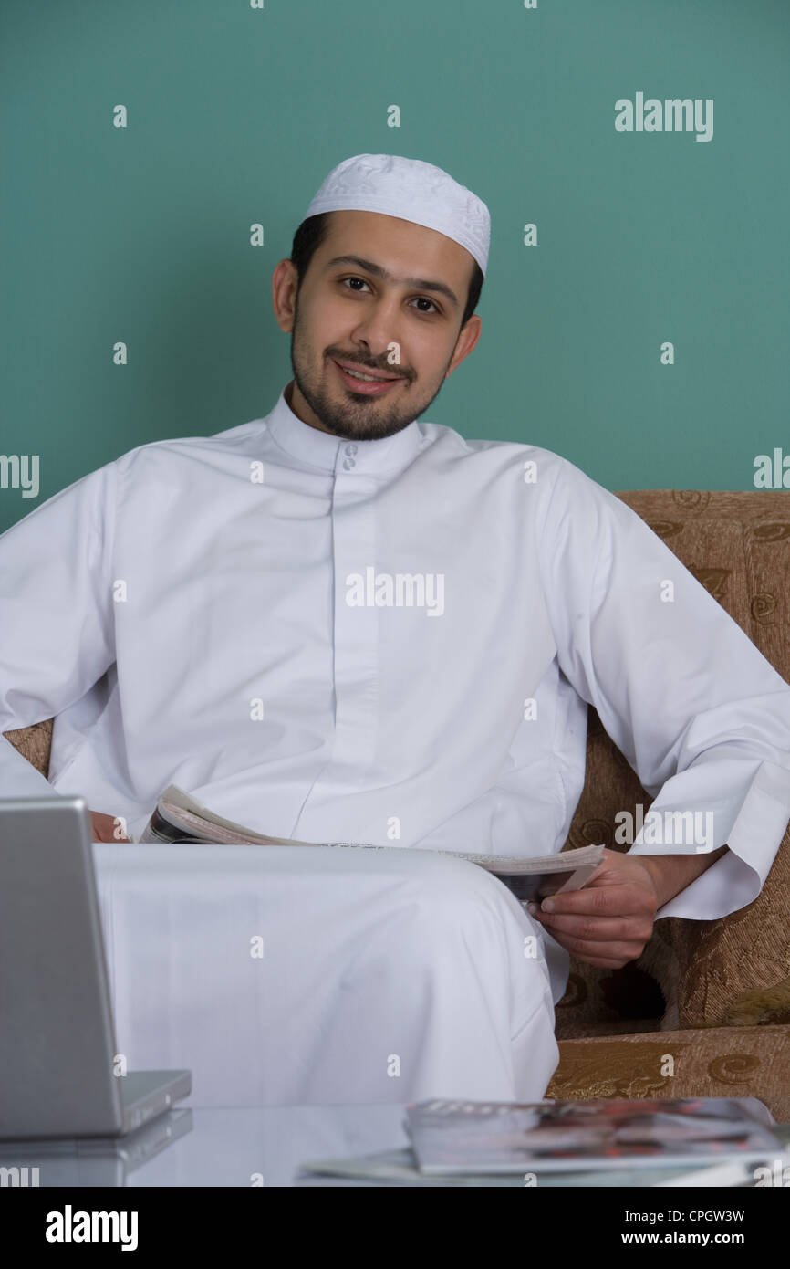 Arab man sitting in the sofa, holding newspaper Stock Photo - Alamy