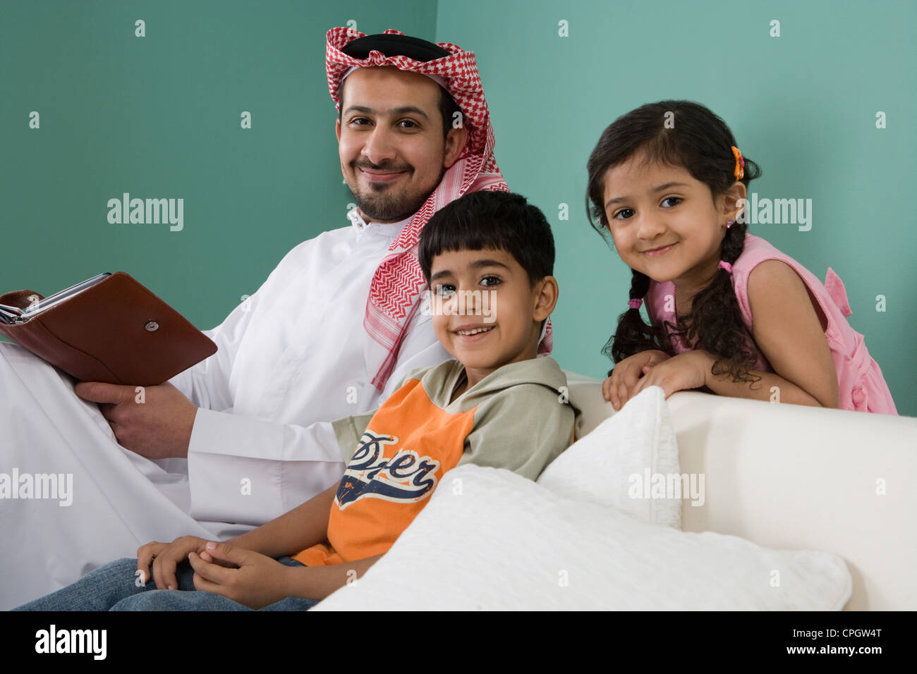Arab father with two children in the sofa, man holding a notebook Stock ...