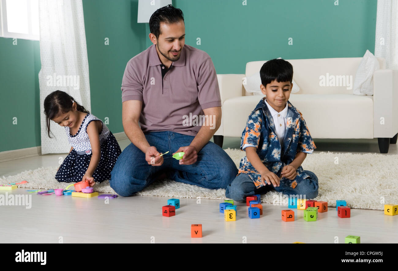 Father with two children playing in the living room Stock Photo - Alamy