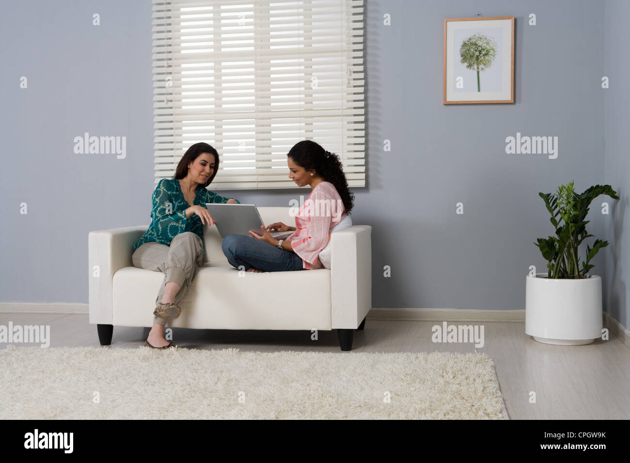 Two women with laptop talking in the living room Stock Photo - Alamy
