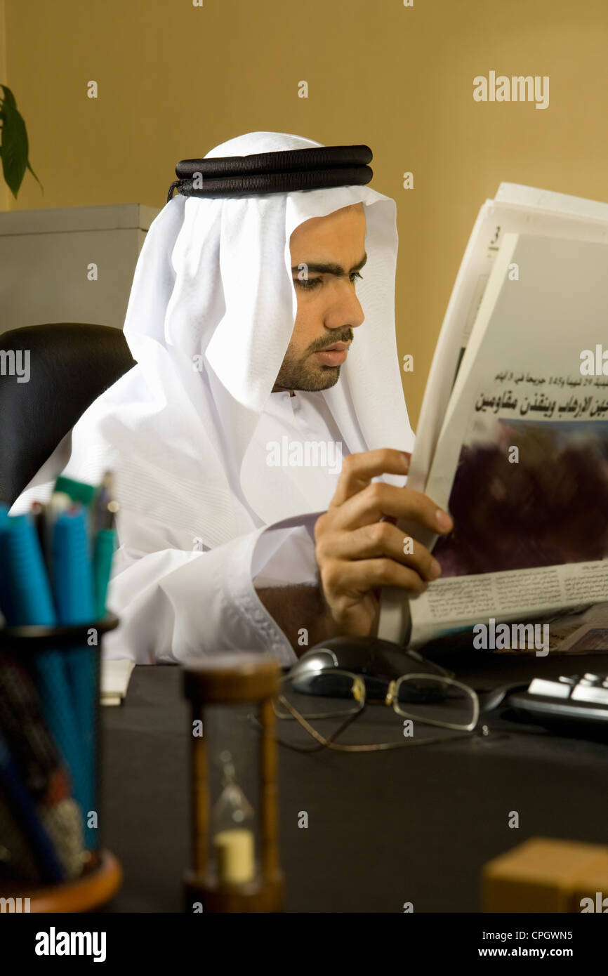 Arab man reading newspaper in office Stock Photo - Alamy