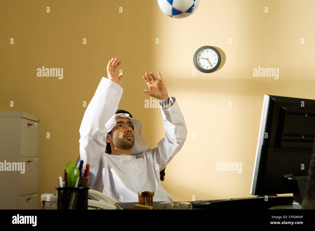 Arab man playing football in office Stock Photo - Alamy