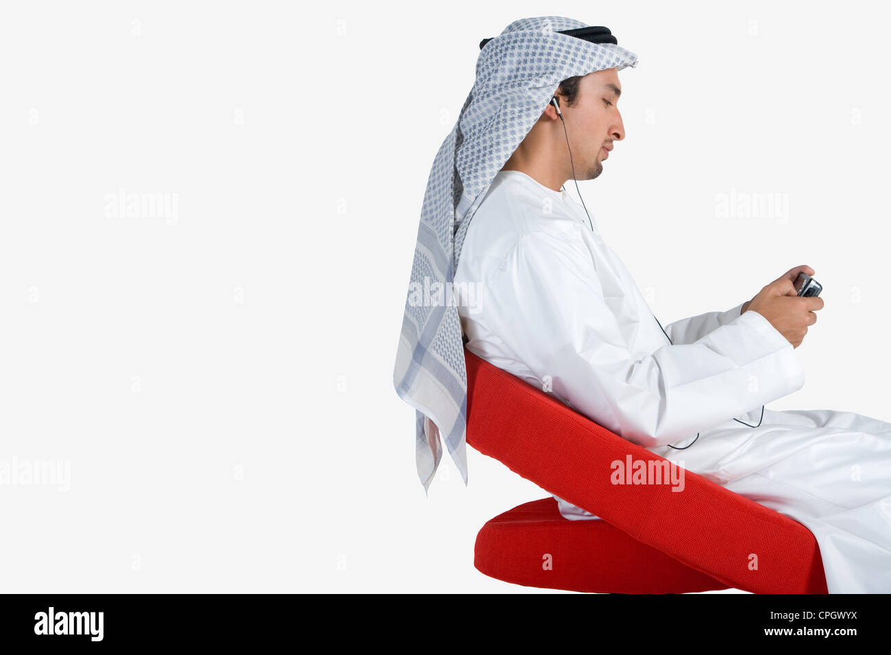 Young man sitting on chair, listening to music, side view Stock Photo ...