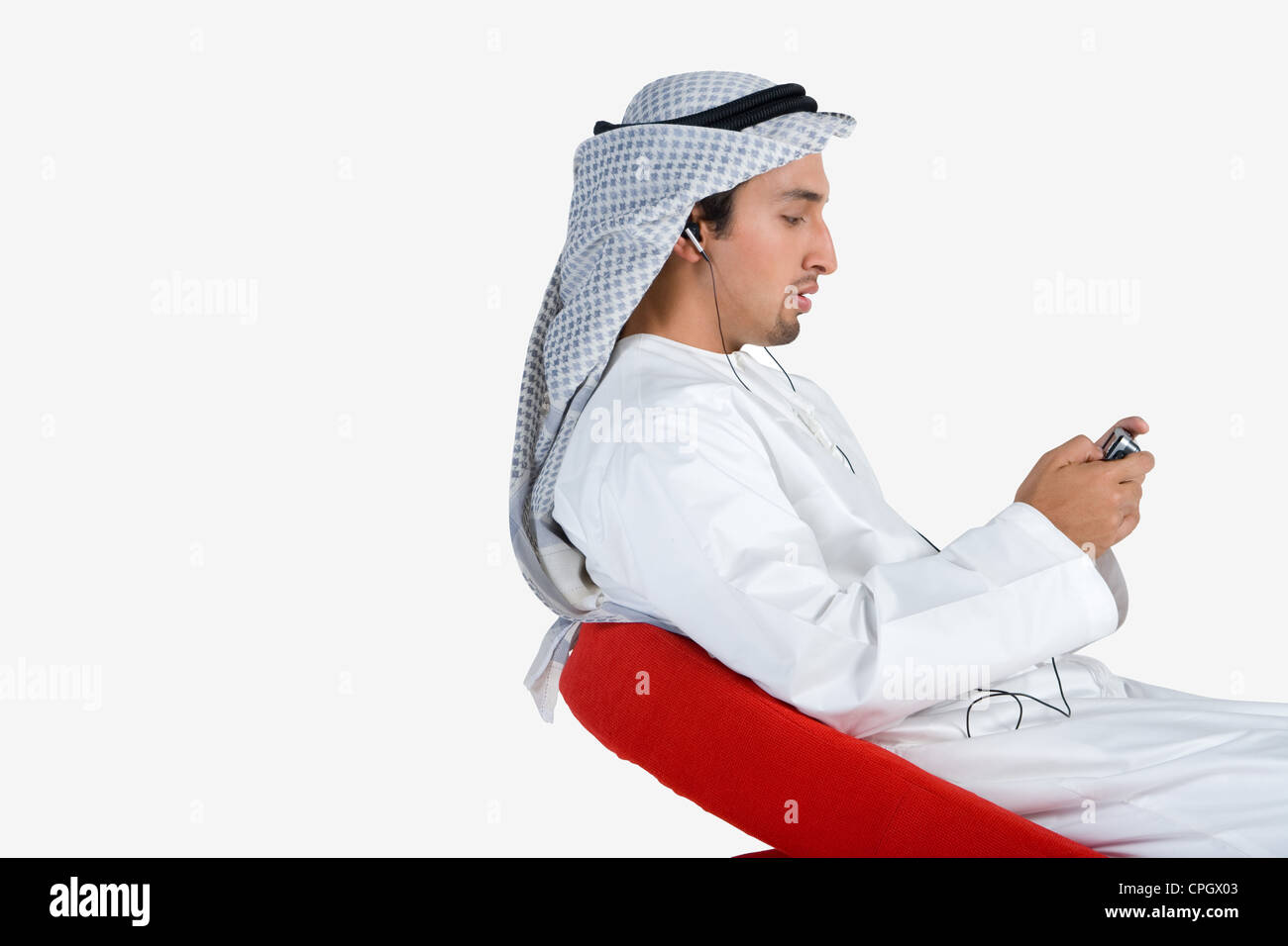 Young man sitting on chair, listening to music, side view Stock Photo ...