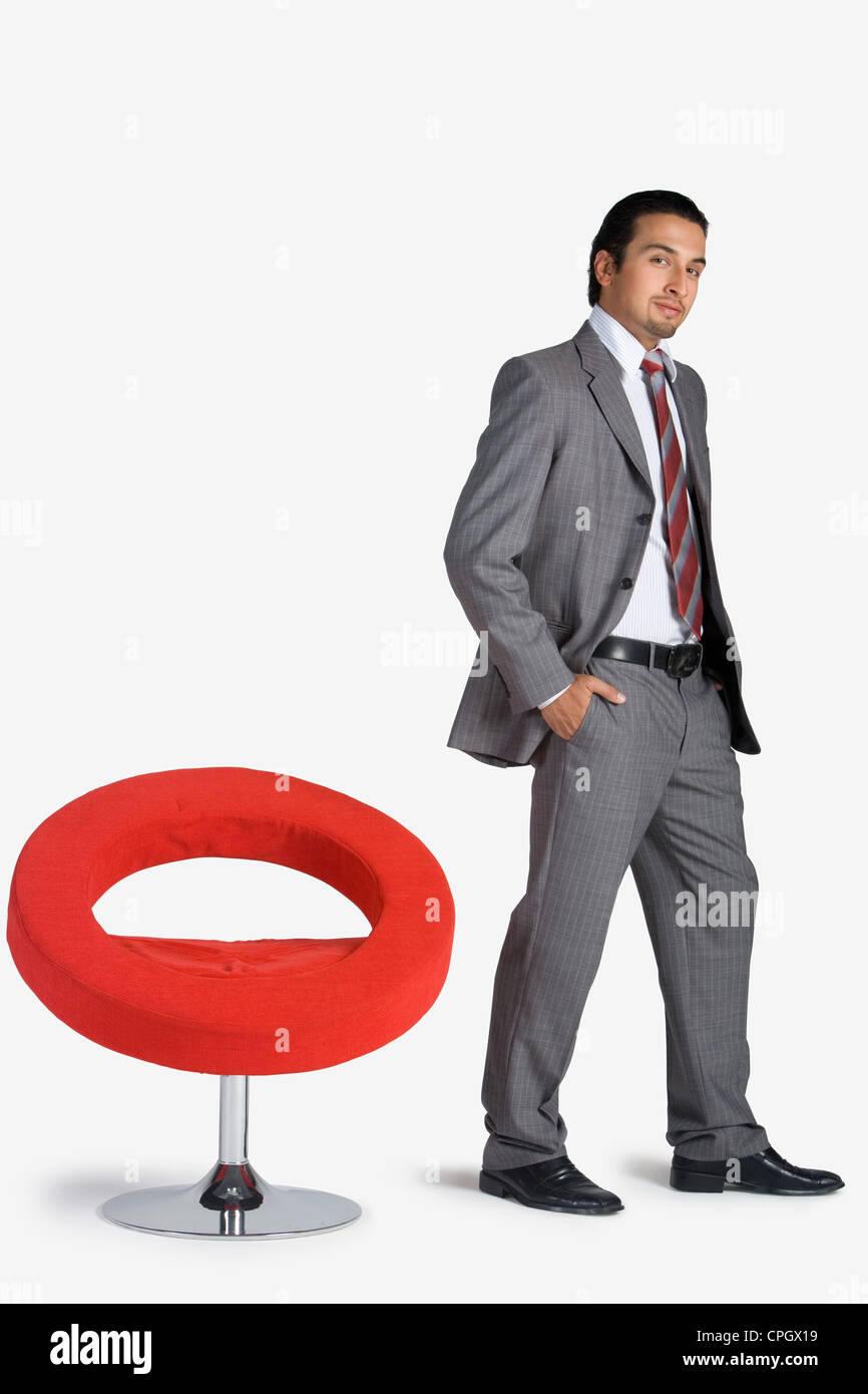 Young businessman standing by swivel chair, portrait Stock Photo - Alamy