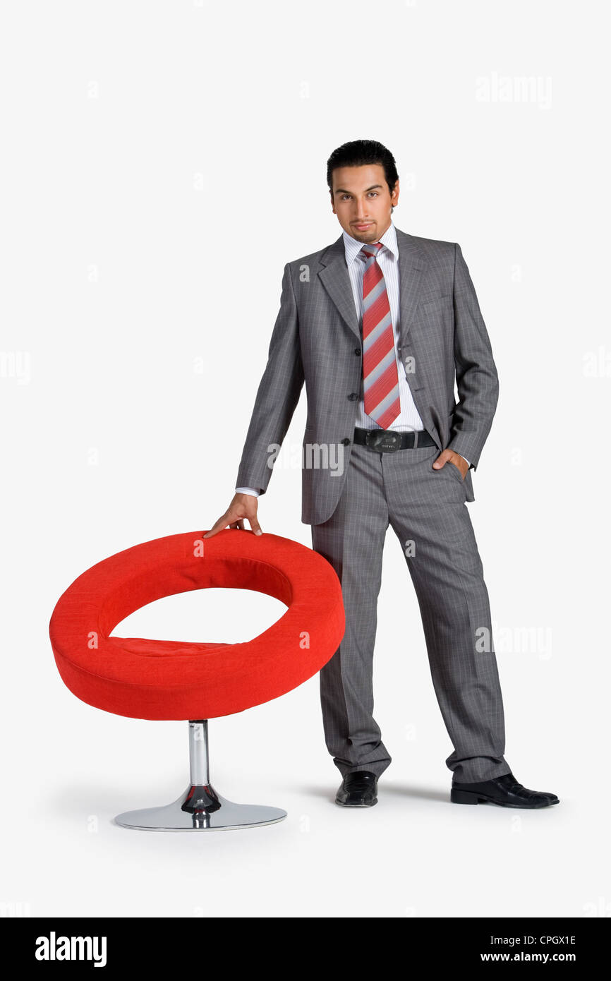 Young businessman standing by swivel chair, portrait Stock Photo - Alamy