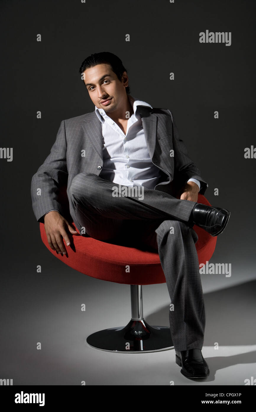 Young man sitting on swivel chair, portrait Stock Photo - Alamy