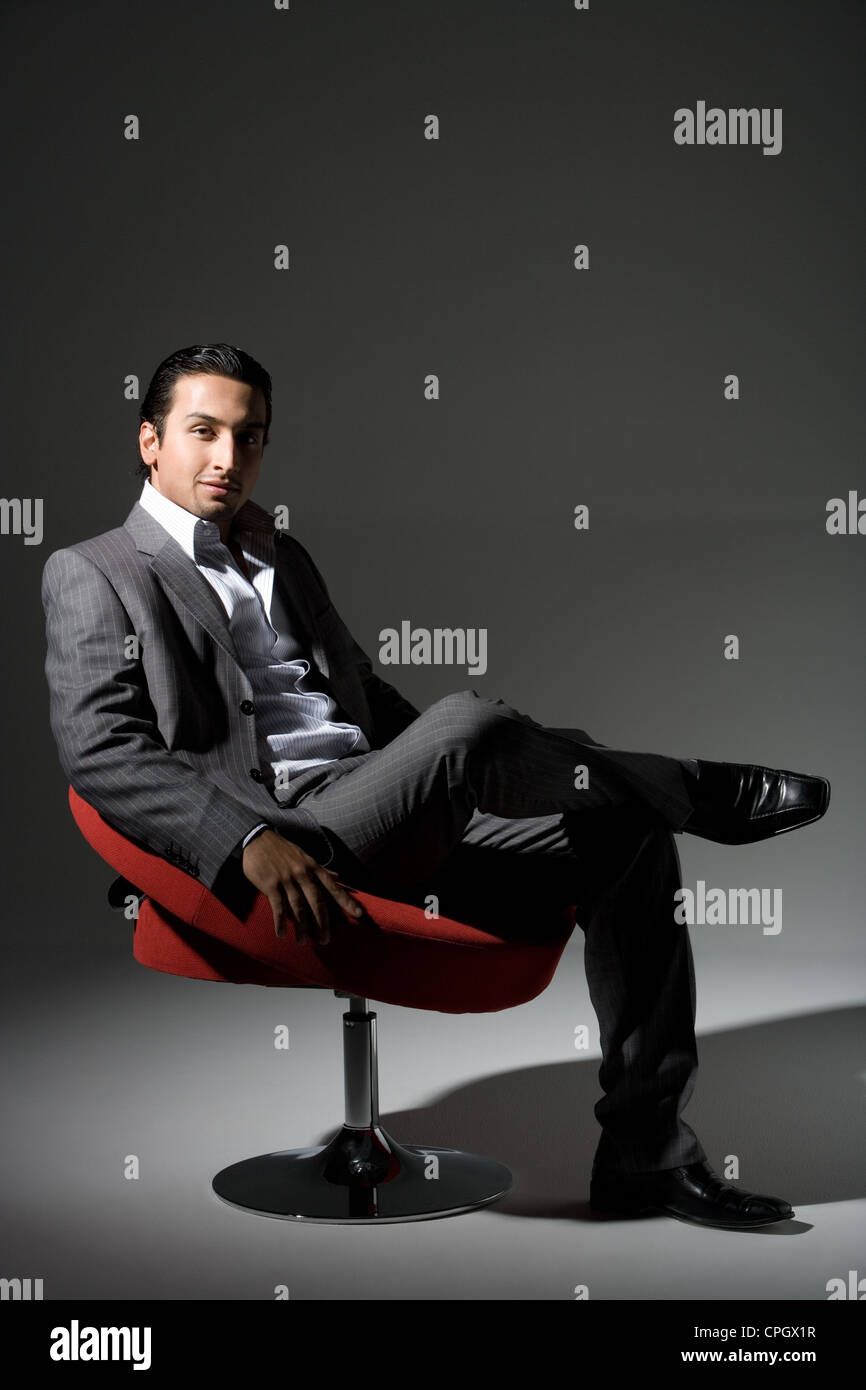 Young man sitting on swivel chair, portrait Stock Photo - Alamy