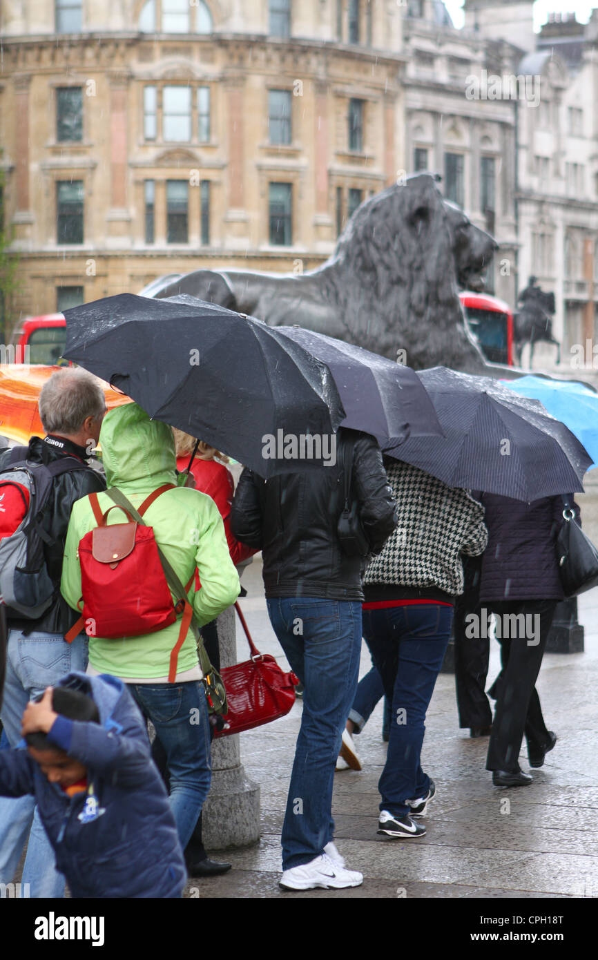 people walking in Trafalgar Square,London, and sheltering under their ...