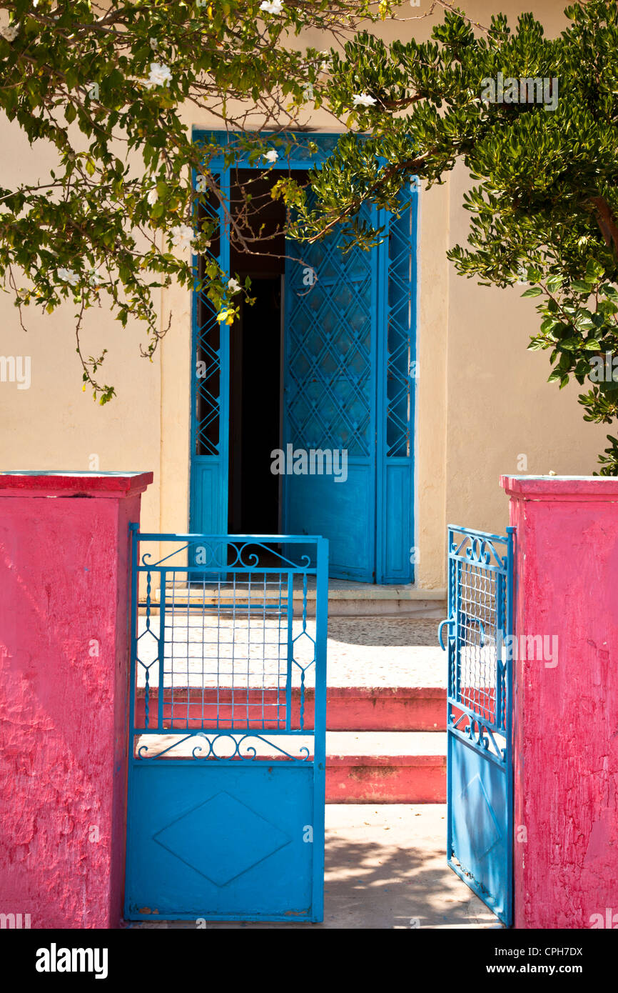 Traditional blue iron gate and door set between bright pink pillars ...