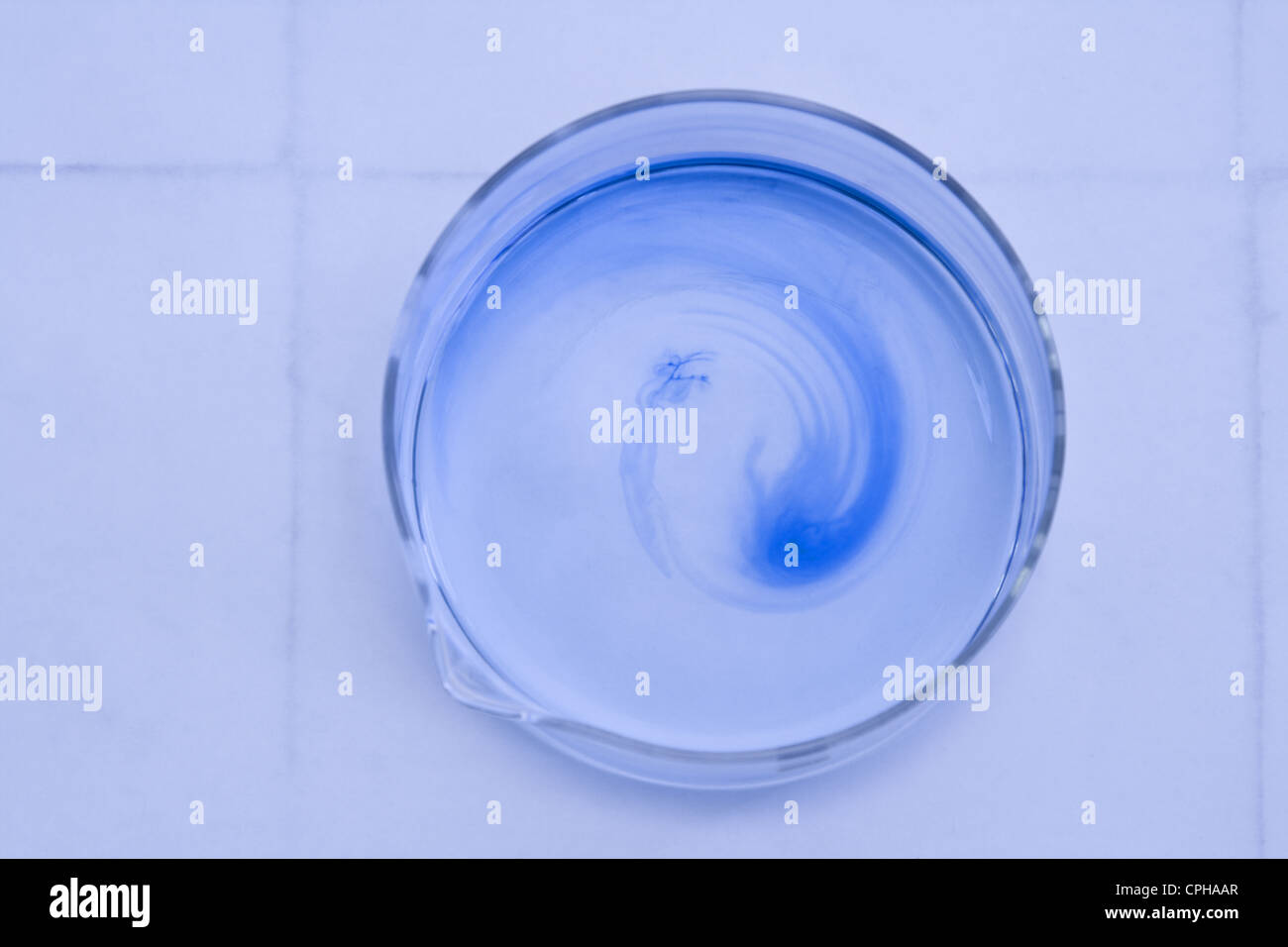 Blue substance dissolving in a glass recipient-upper view,blue tones ...