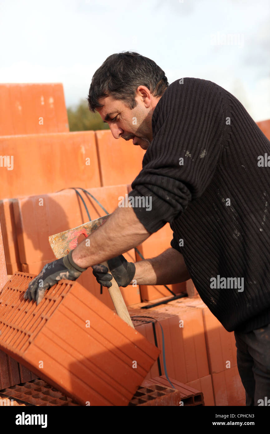 Mason making adjustments to brick Stock Photo - Alamy