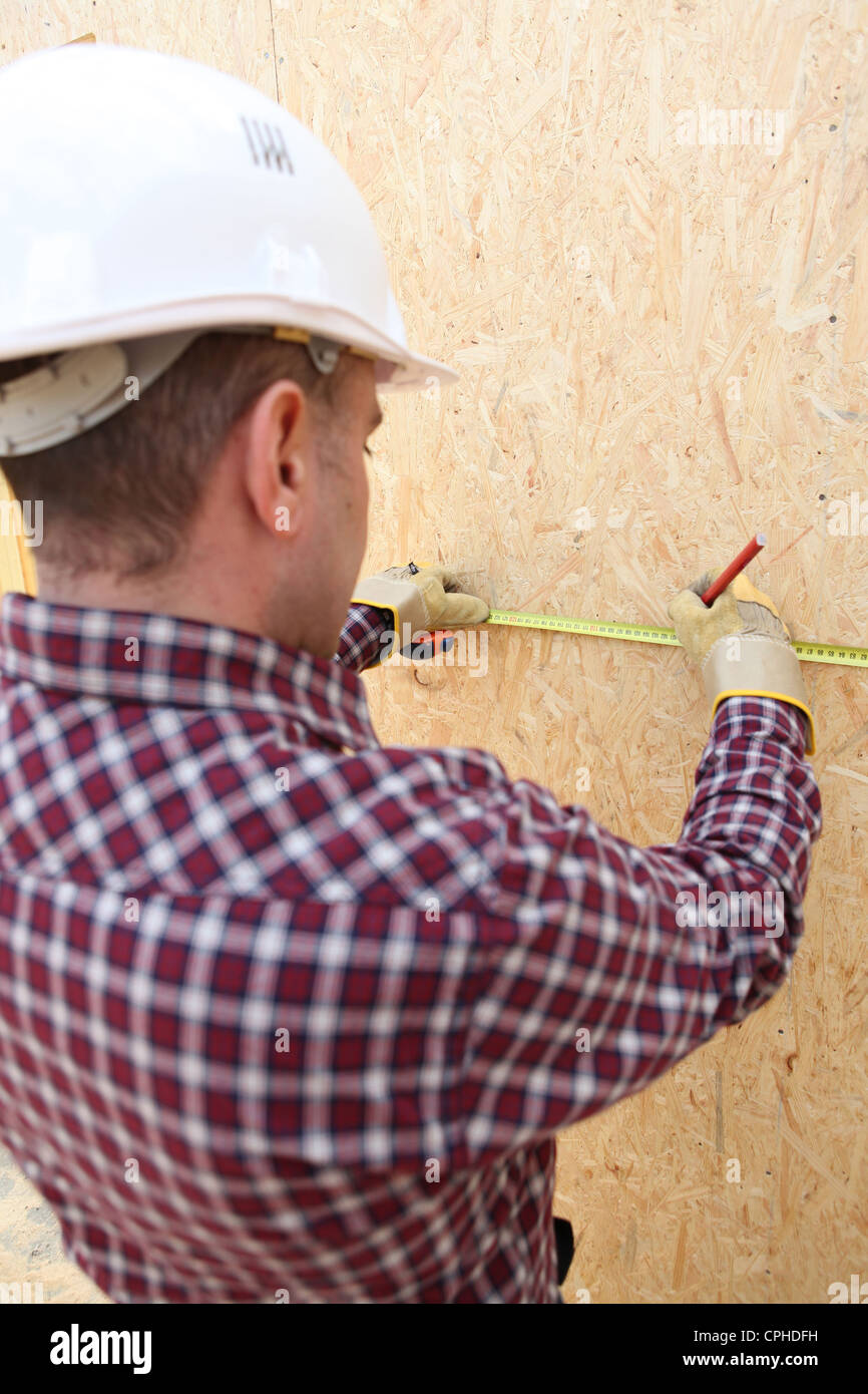 Man using tape measure to mark wooden panel Stock Photo - Alamy