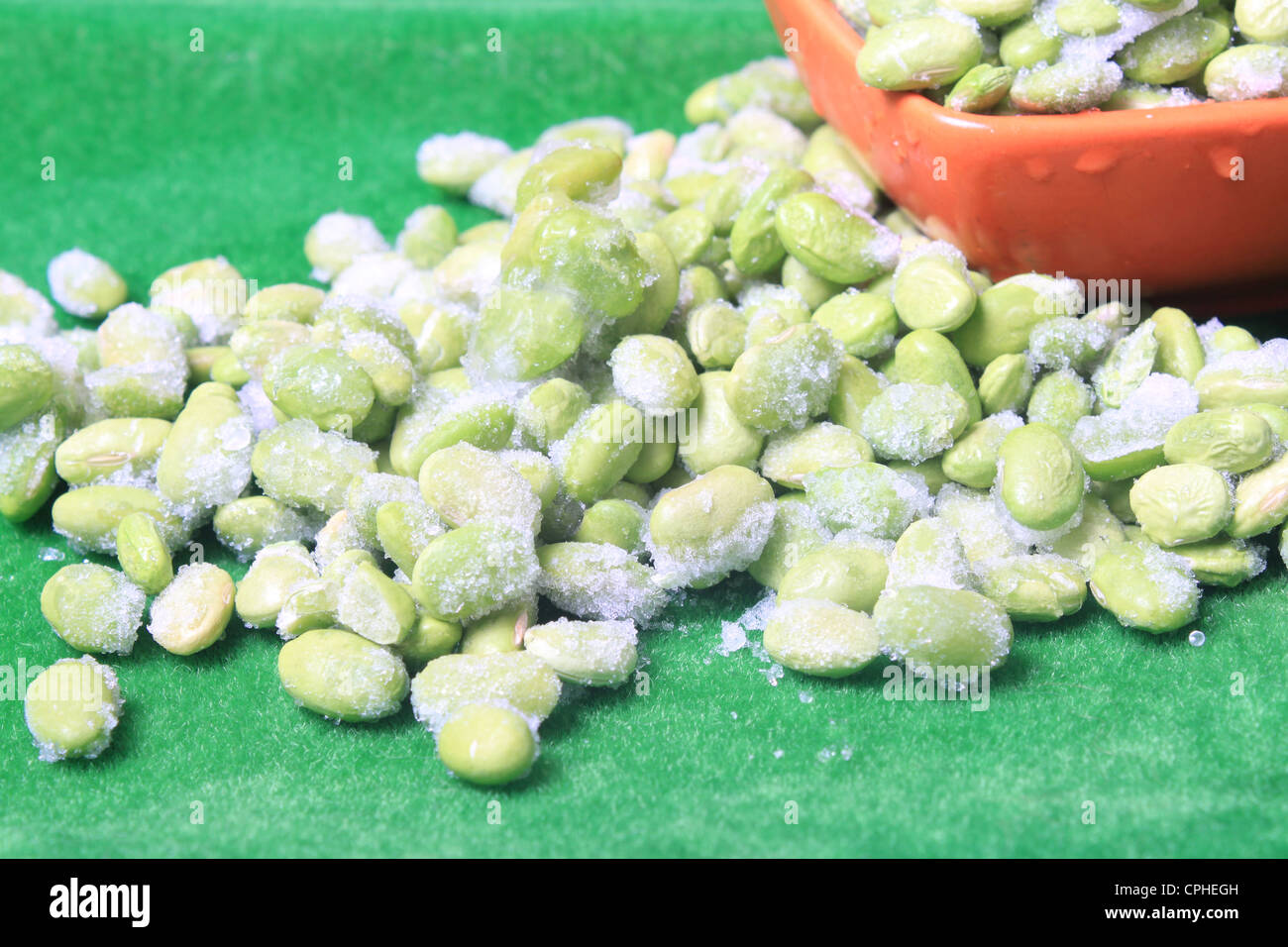 Frozen edamame also known as soybeans in a bowl on a green background ...