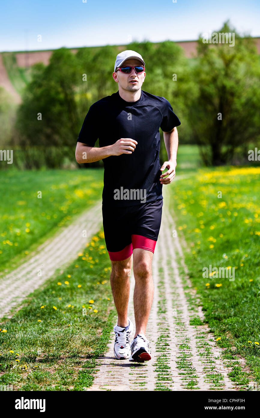 a young man jogging through the fields Stock Photo - Alamy