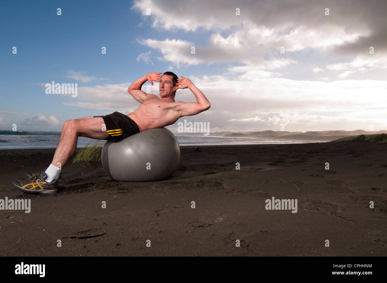 Man training on beach with exercise ball Stock Photo - Alamy