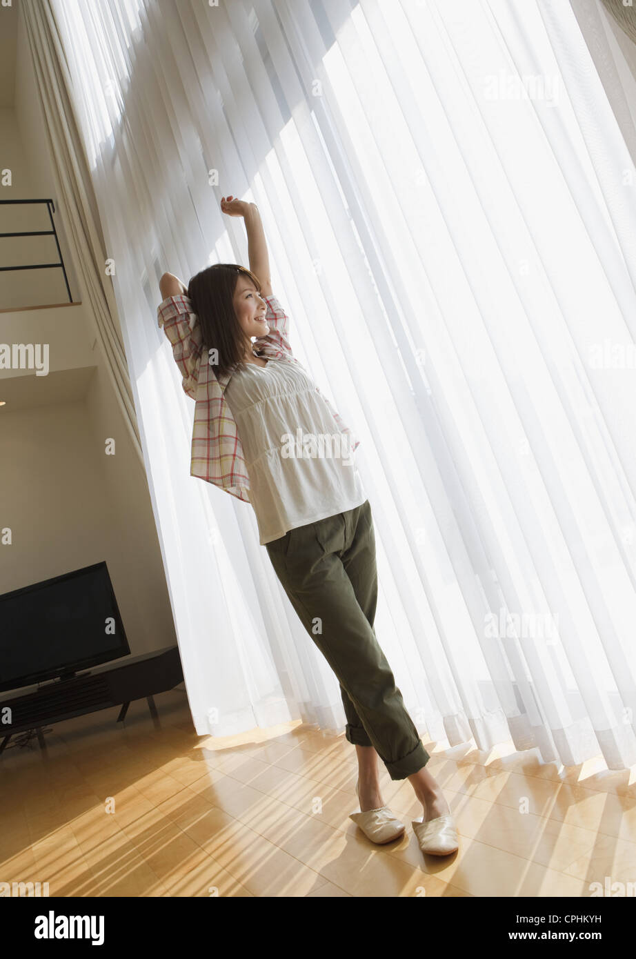 Middle-aged woman stretching by a window Stock Photo - Alamy
