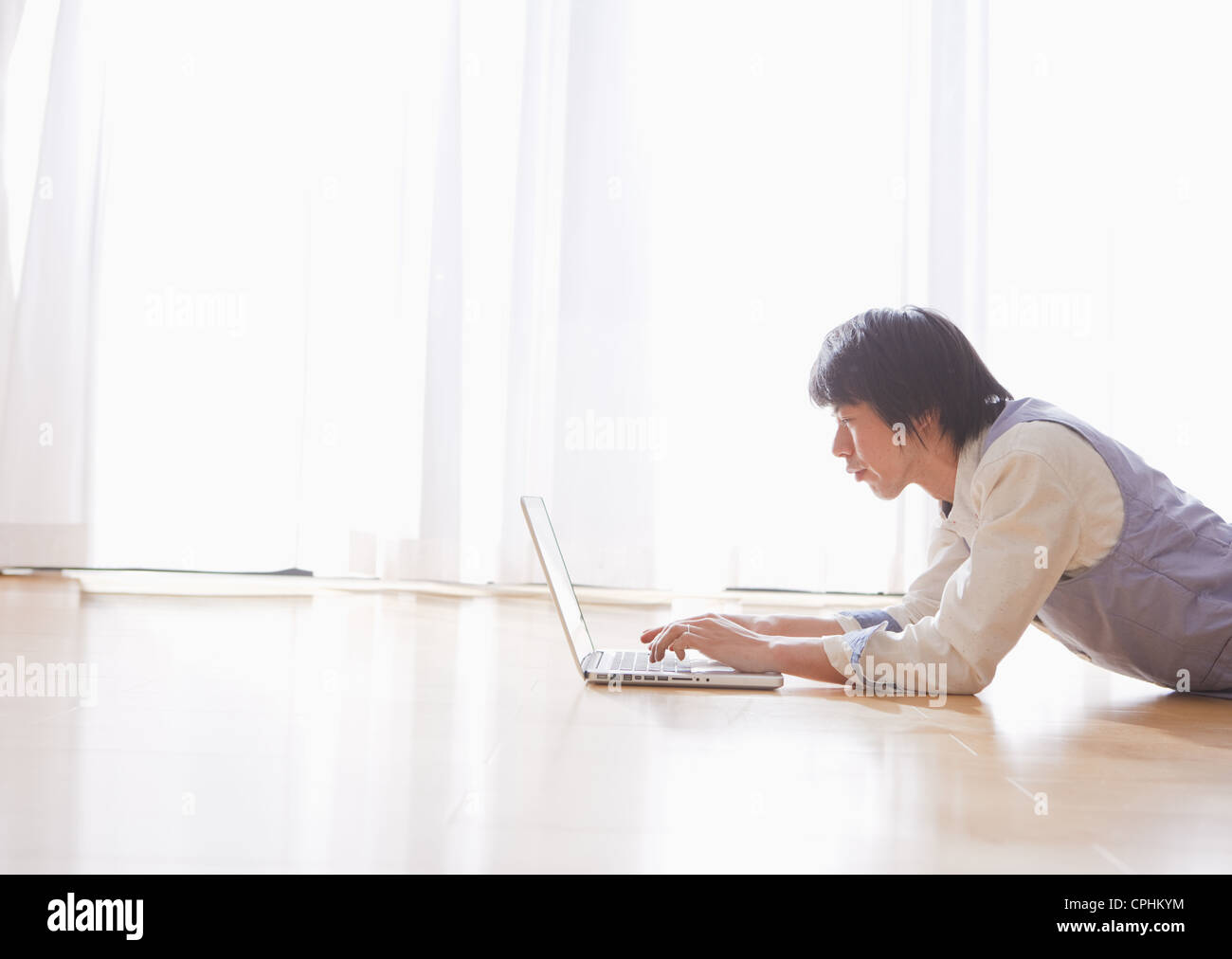 Middle-aged man using a laptop by a window Stock Photo - Alamy