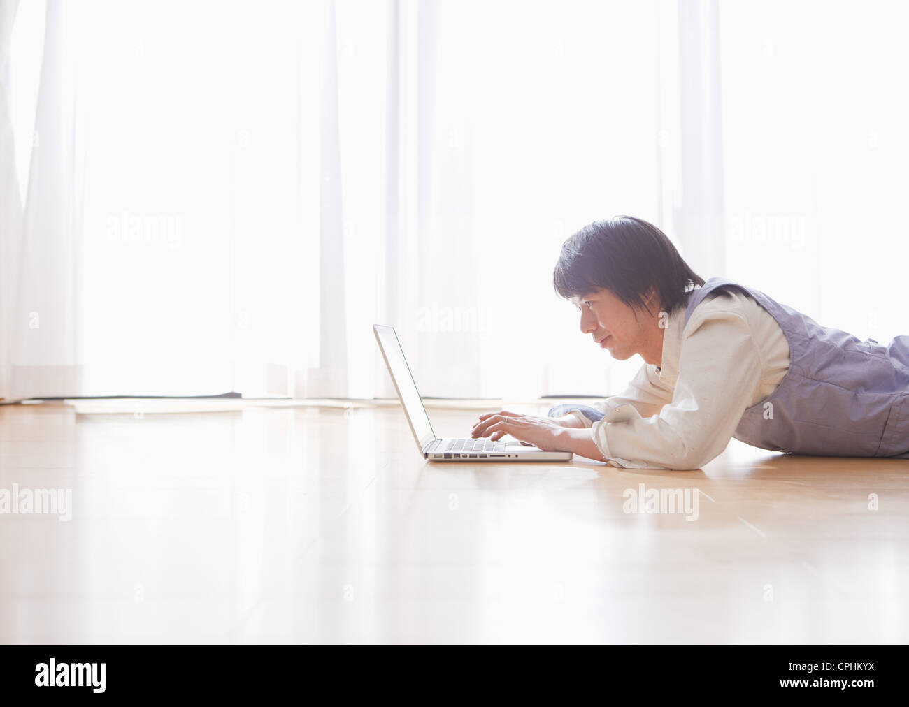 Middle-aged man using a laptop by a window Stock Photo - Alamy