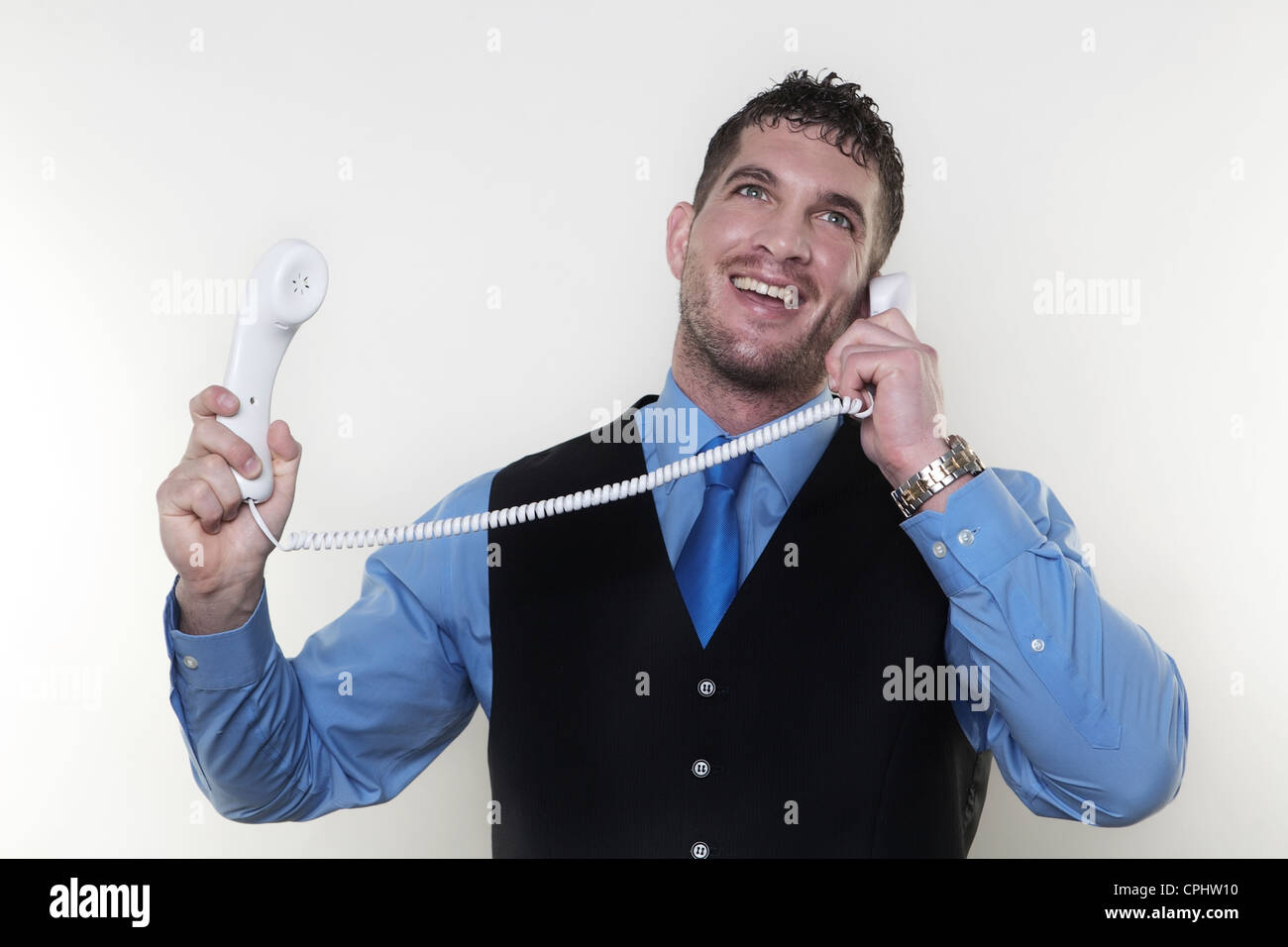 handsome man holding up two phones connected by a single telephone wire ...