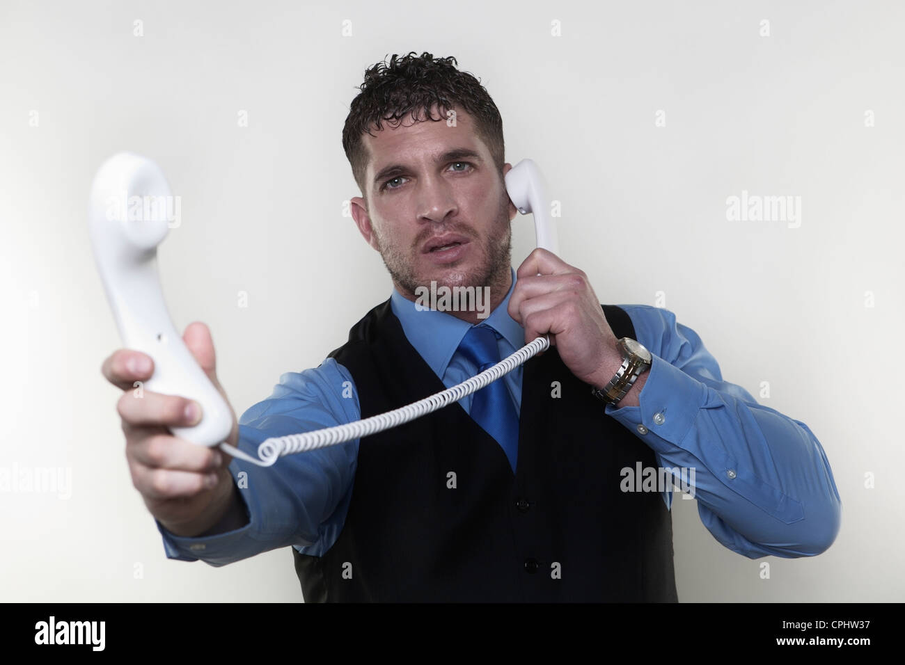 handsome man holding up two phones connected by a single telephone wire ...