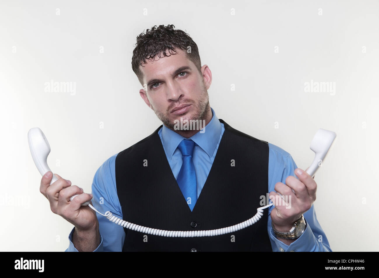 handsome man holding up two phones connected by a single telephone wire ...