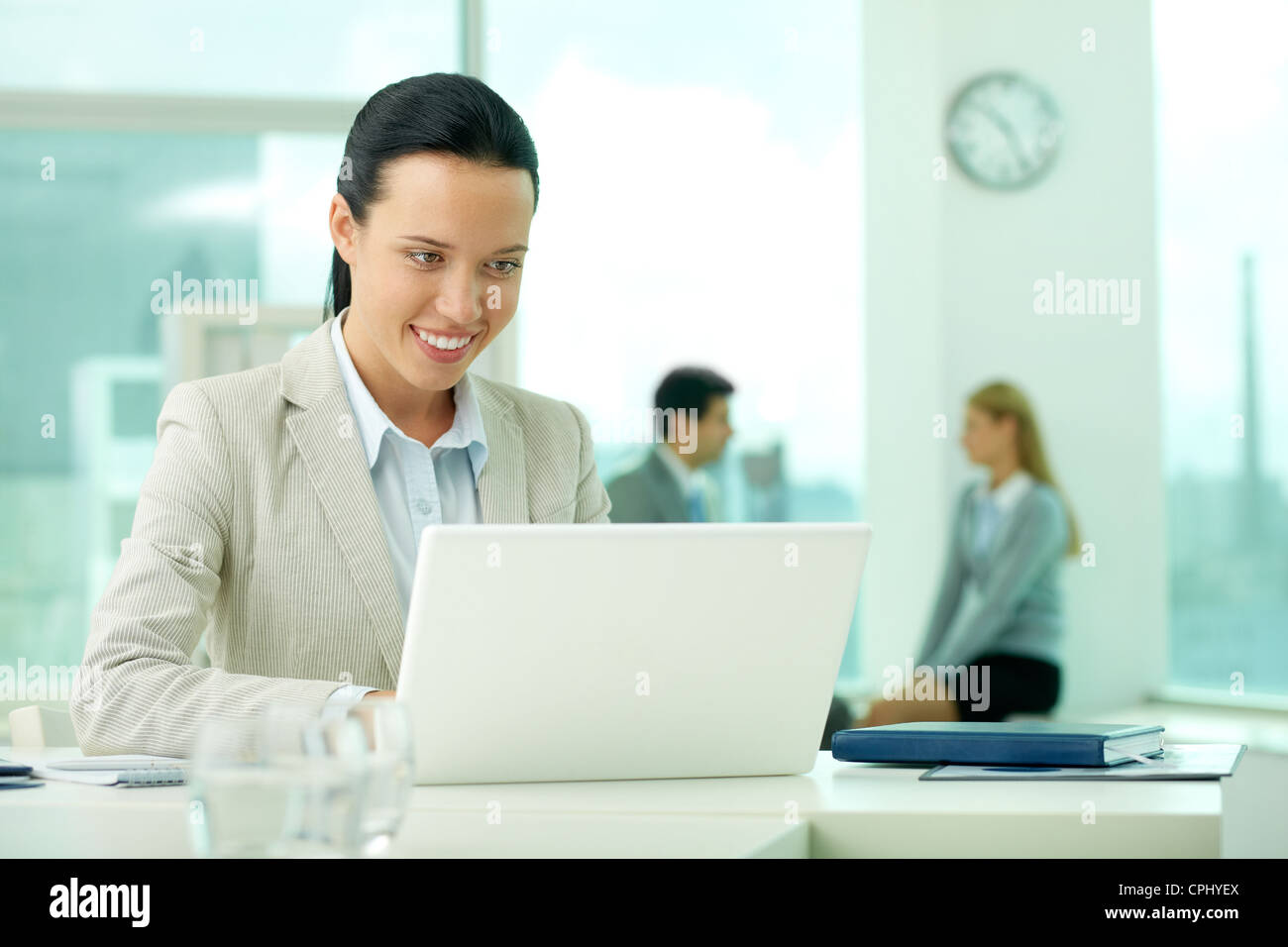 Portrait of pretty secretary looking at laptop screen while typing ...