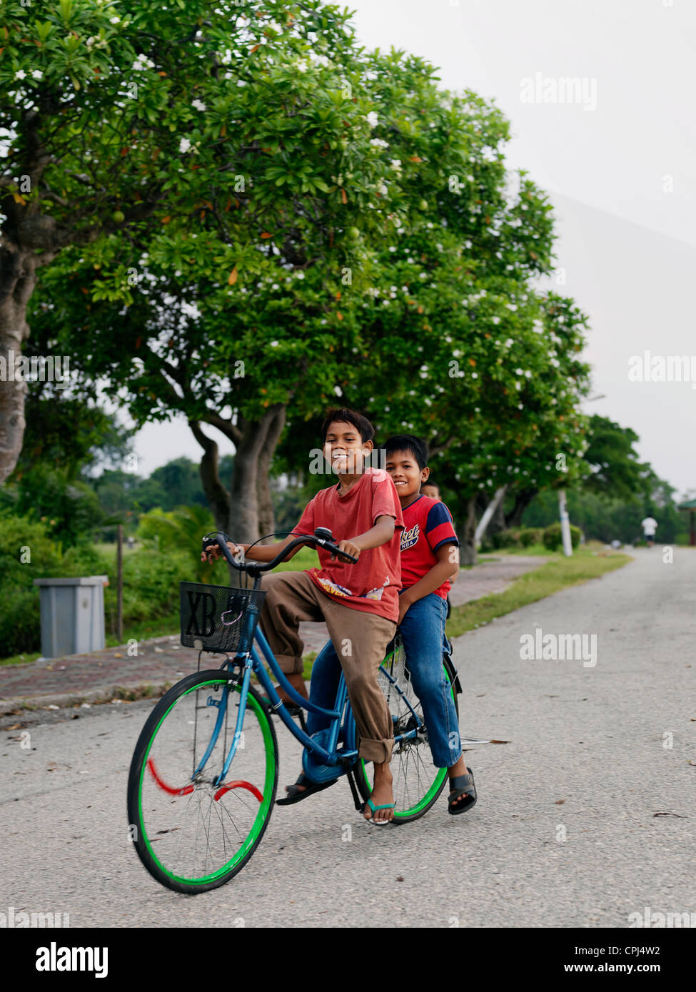 Two boys sharing a bicycle Stock Photo - Alamy