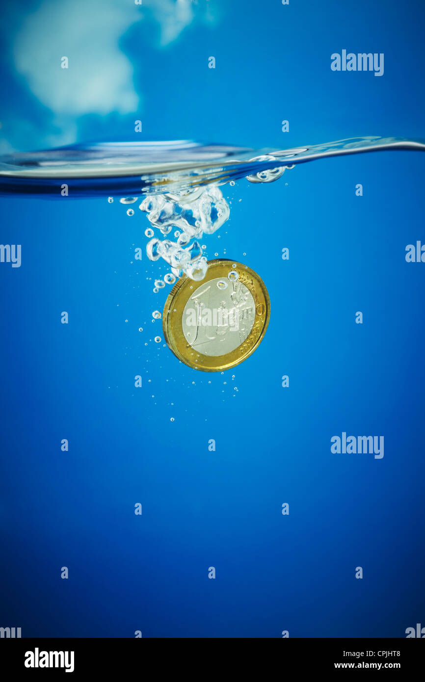 1 Euro coin sinking in blue water Stock Photo - Alamy