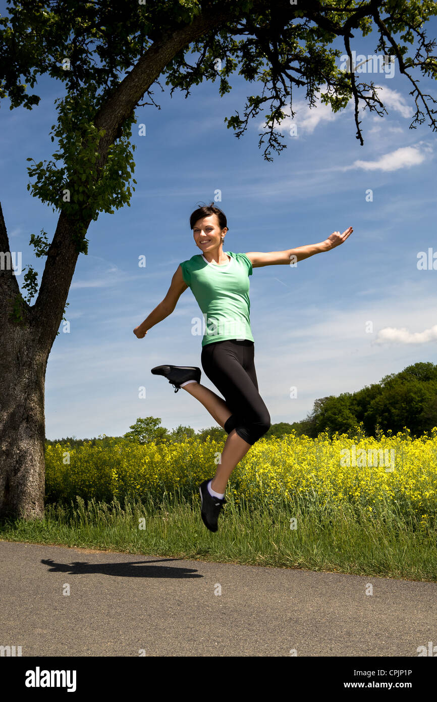 a young jumping woman in front of rural landscape Stock Photo - Alamy