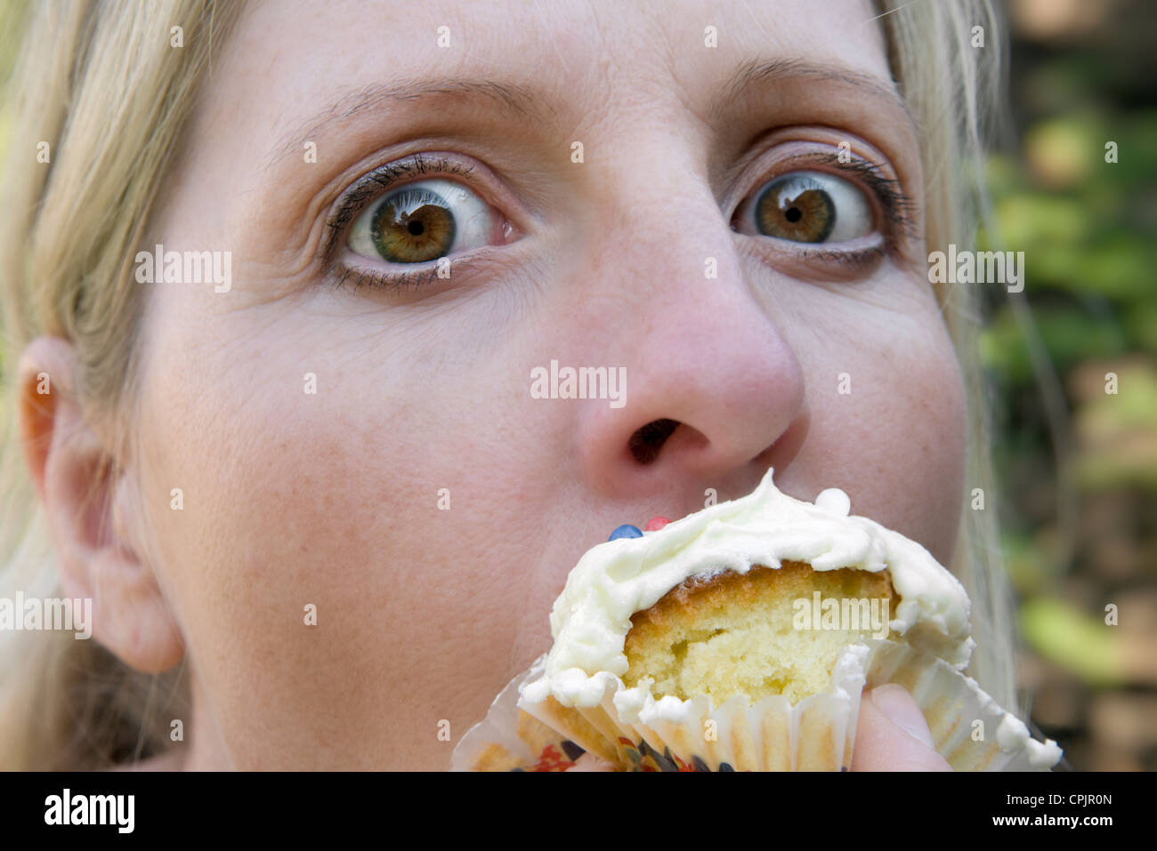 Closeup of woman eating cupcake with eyes wide in surprise. concept of ...