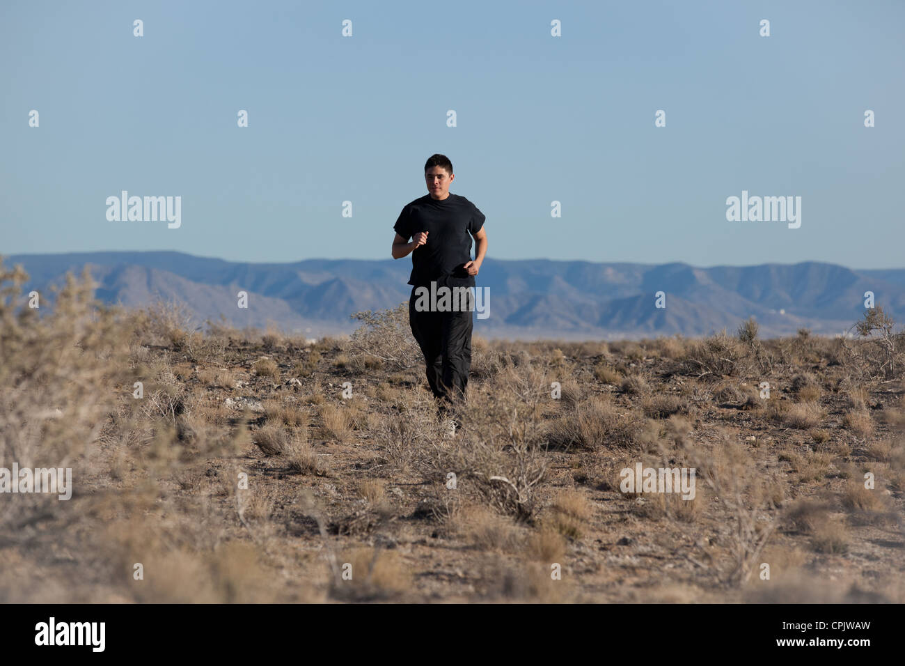 Athletic Hispanic young man running through the desert in Albuquerque ...
