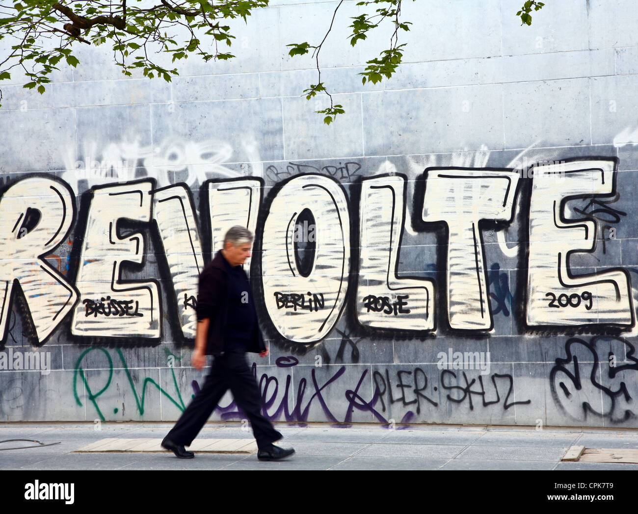 people passing by a large graffiti "revolte" on a wall Stock Photo - Alamy