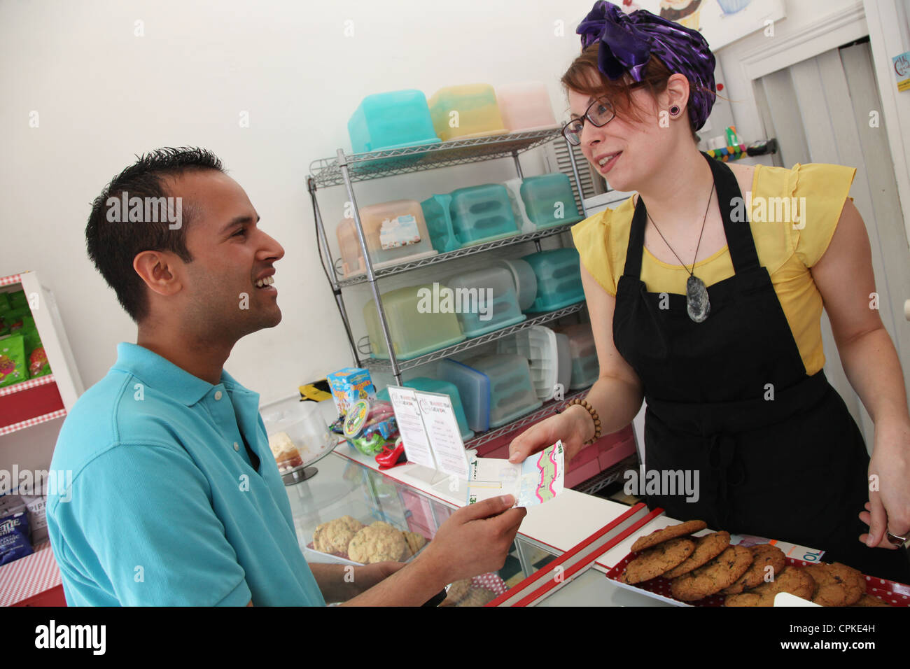 A man pays for cupcakes with the Brixton Pound, a local currency which ...