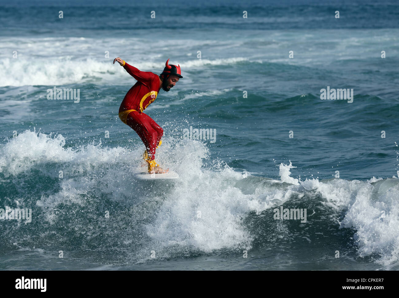Man surfing a wave wearing a superhero costume Stock Photo - Alamy
